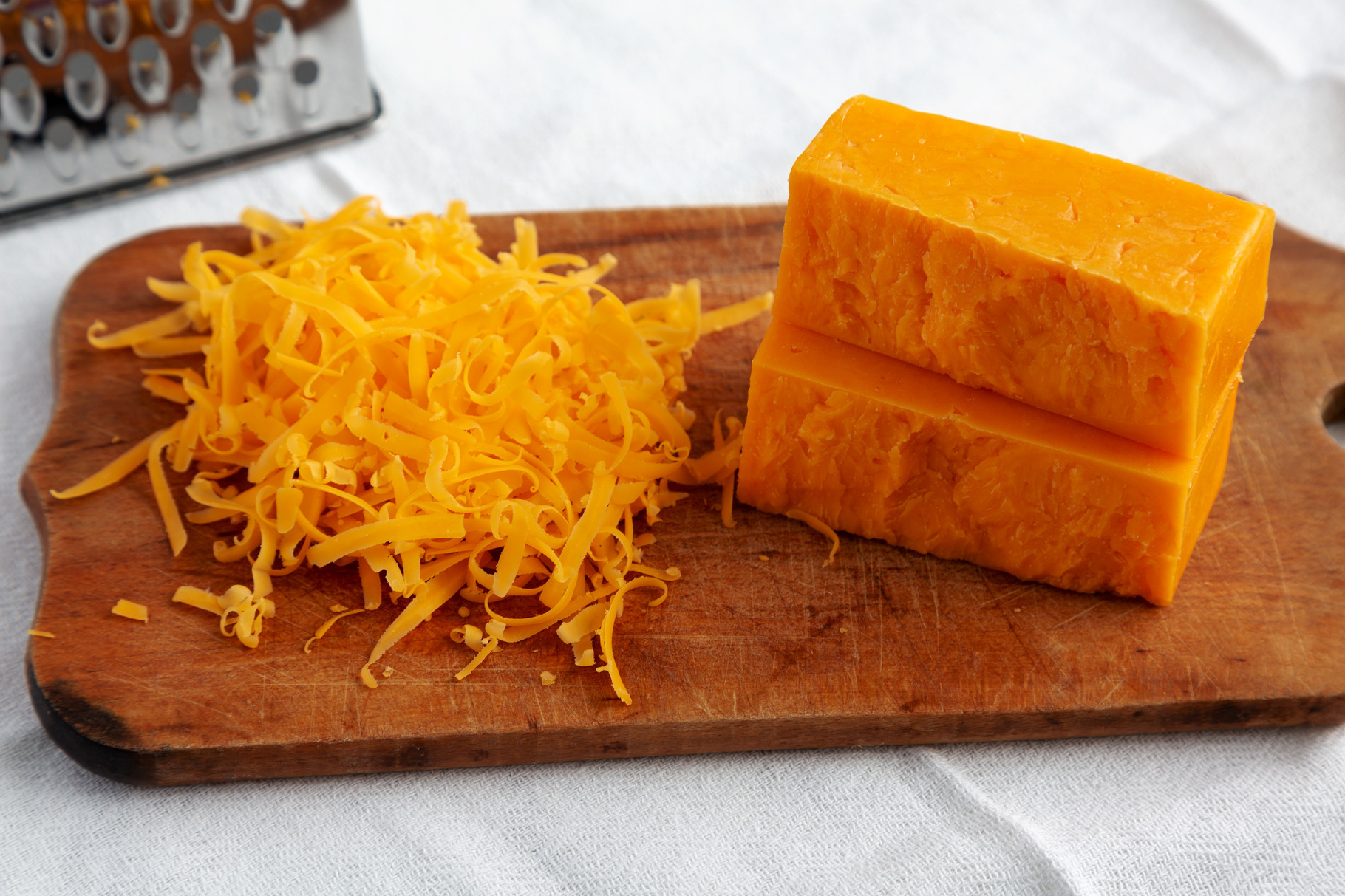 Shredded Sharp Cheddar Cheese on a rustic wooden board, side vie, a ...