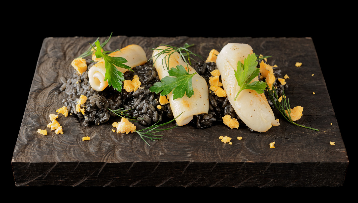 Black risotto cooked with squid ink featuring calamary, calamari, and ...