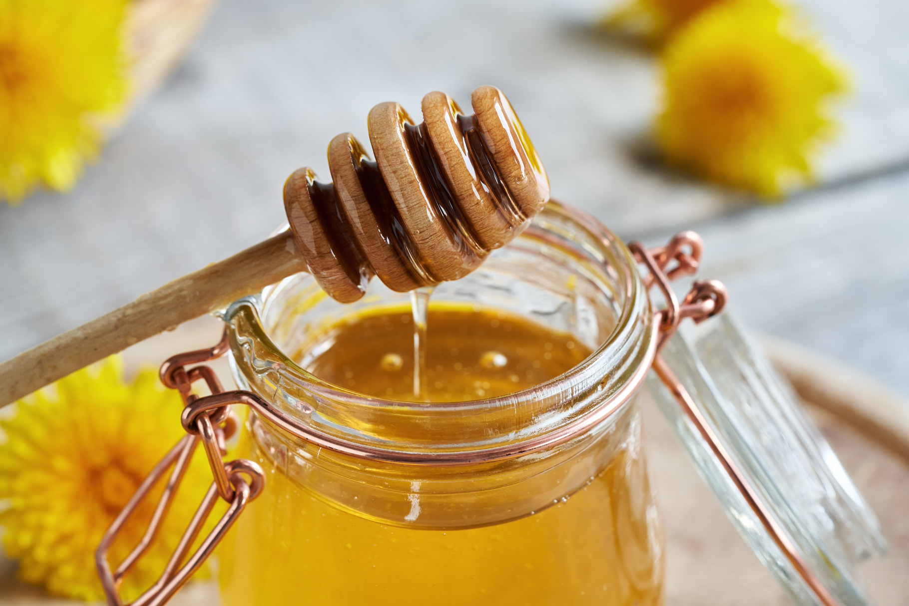 Honey dipper and a glass of dandelion honey made from fresh flow, a ...