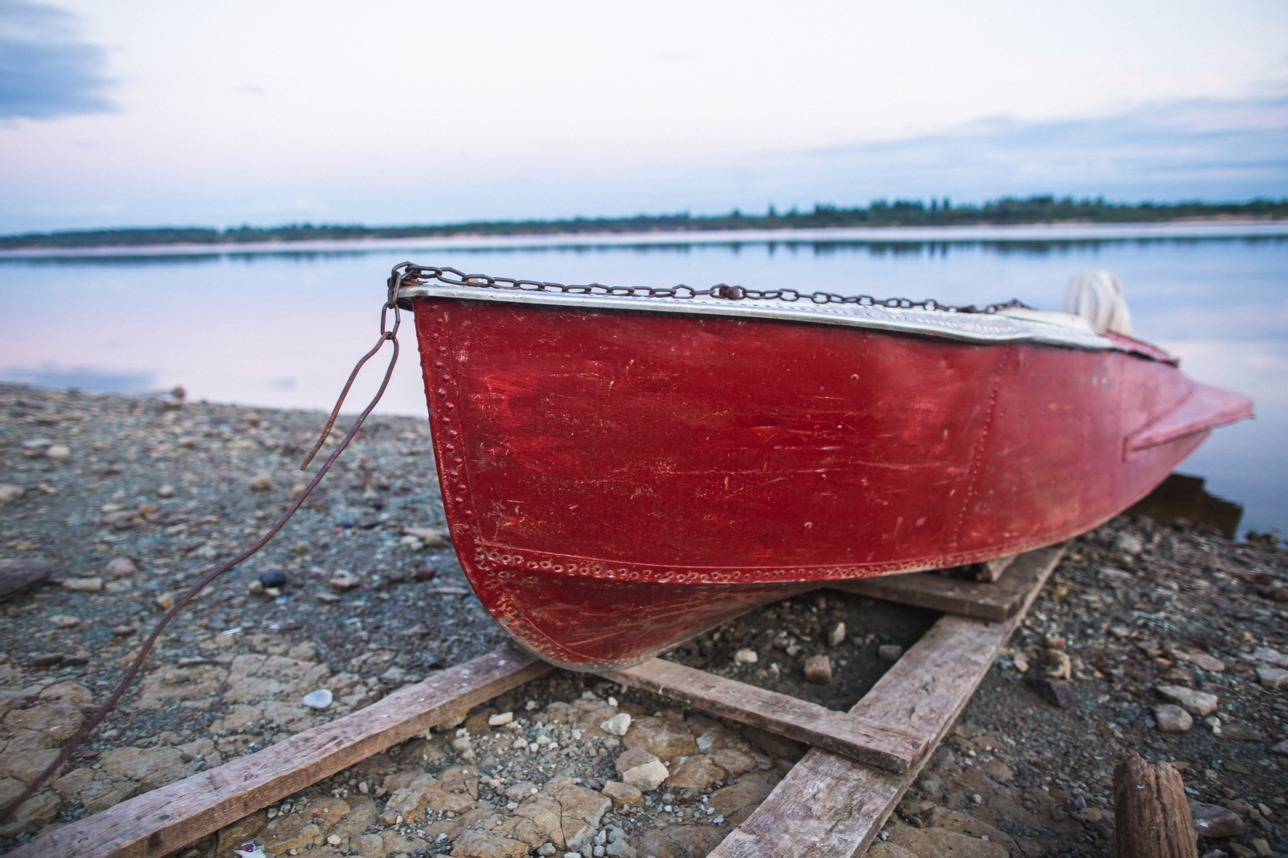 Old red rowboat lying at shore featuring red, boat, and motor, a ...