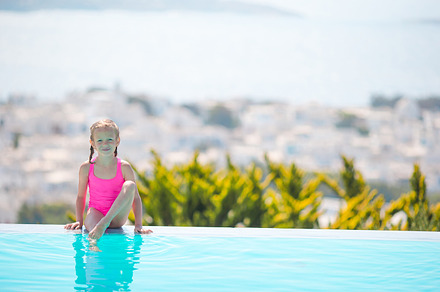 Adorable little girls on the edge of outdoor swimming pool with ...
