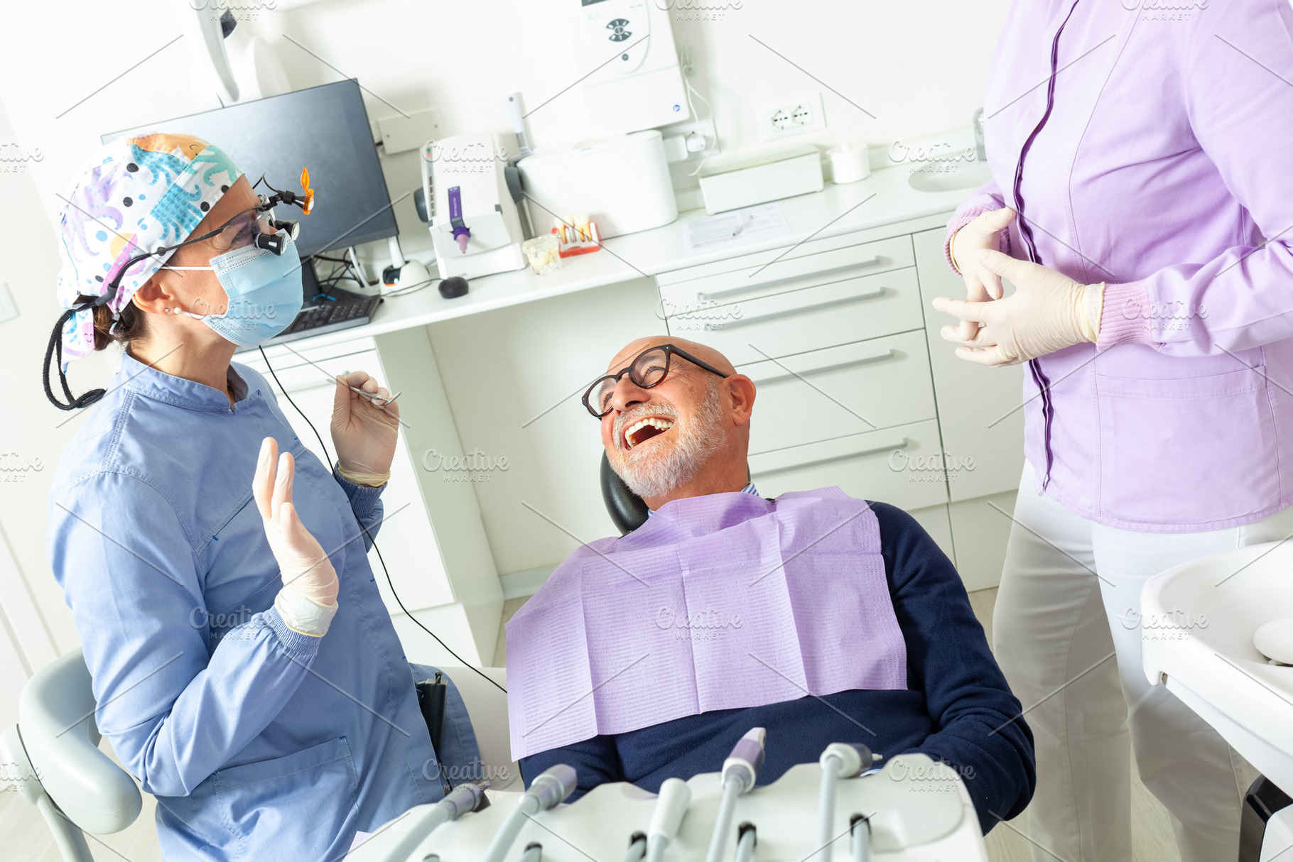 Senior man laughing during dental checkup with female dentist and ...