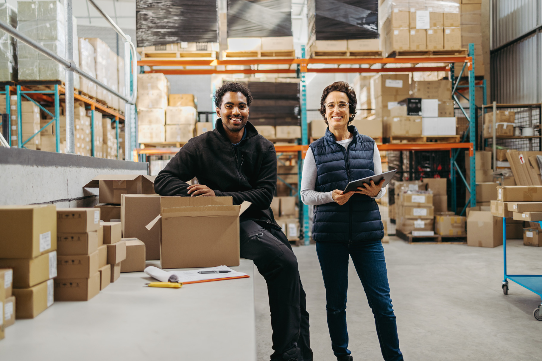 Happy warehouse employees smiling at the camera in a logistics centre ...