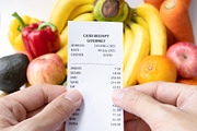 Hands hold shopping receipt bill with variety of colorful fresh, a ...