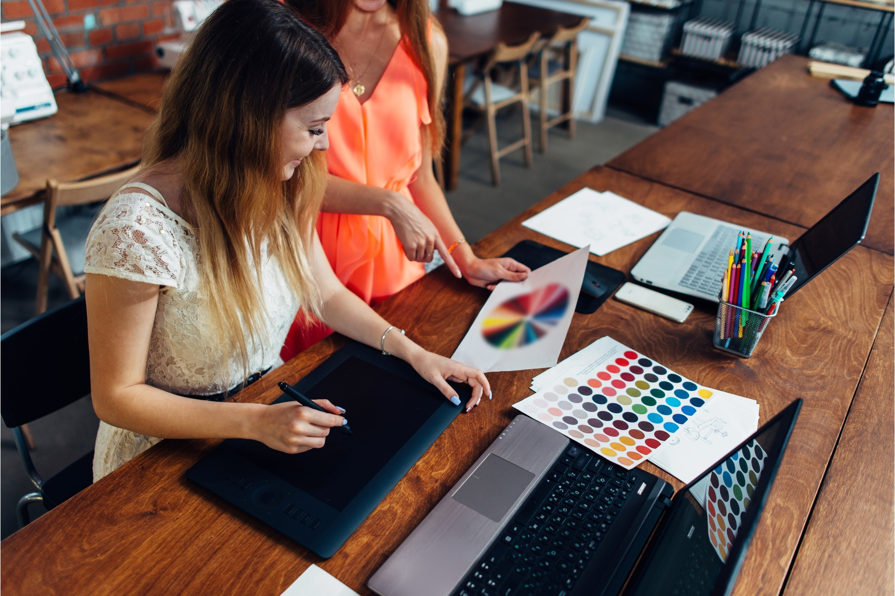 Female designer working with client at desk in her office, a Person ...