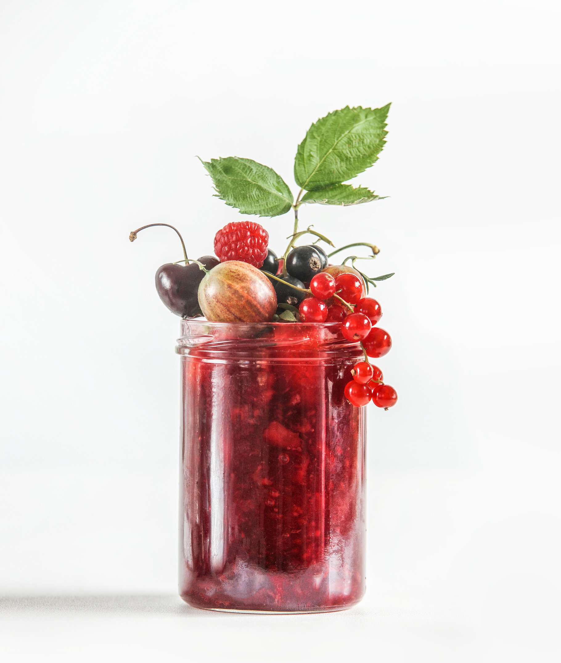 Red jam in jar with various berries