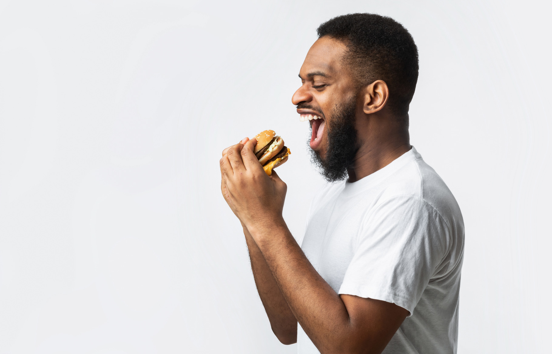 Side View Of Hungry Black Man Eating Burger, White Background, a ...