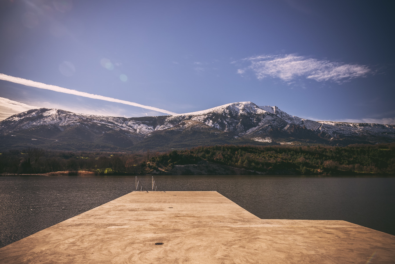 Concrete pier in a lake shore featuring lake, pier, and mountains, a ...