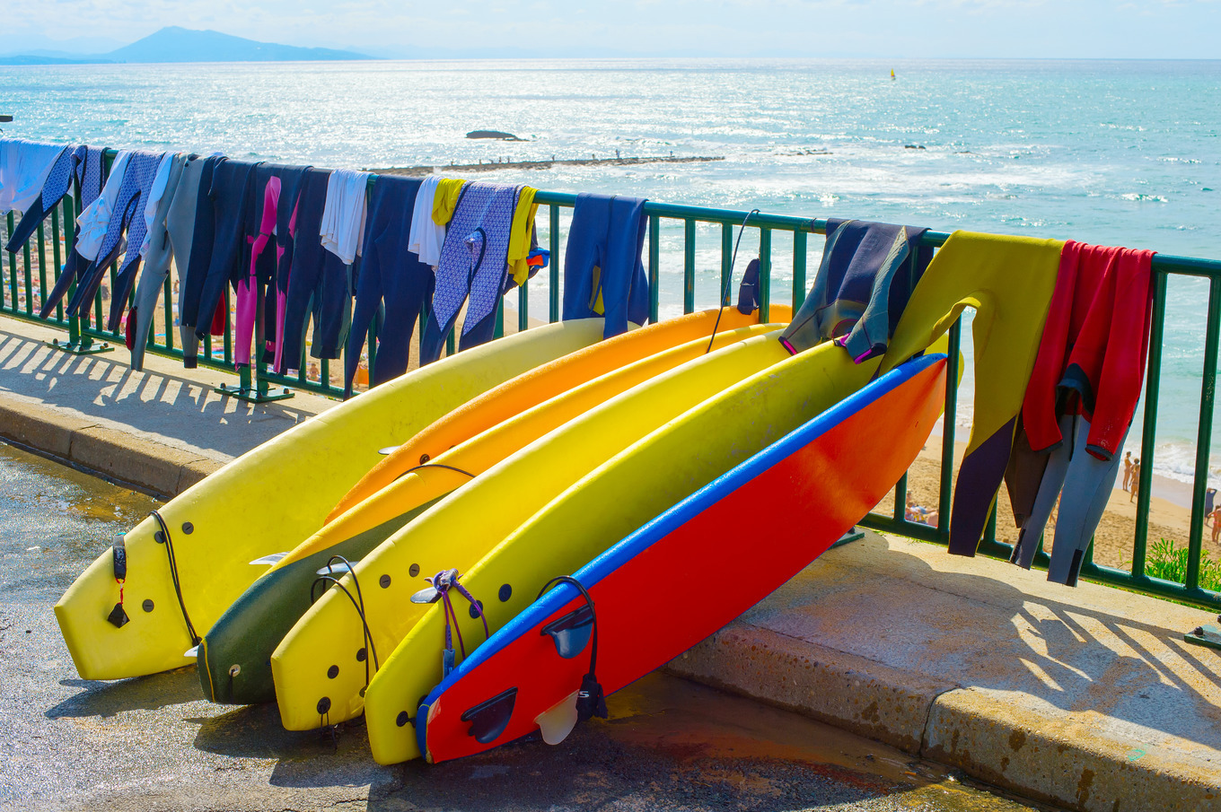Surfboards and wetsuits drying featuring beach, surf, and surfer, a ...