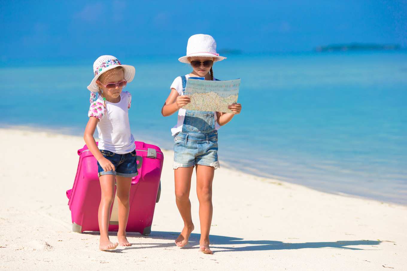 Little girls with big suitcase and map at tropical beach containing ...