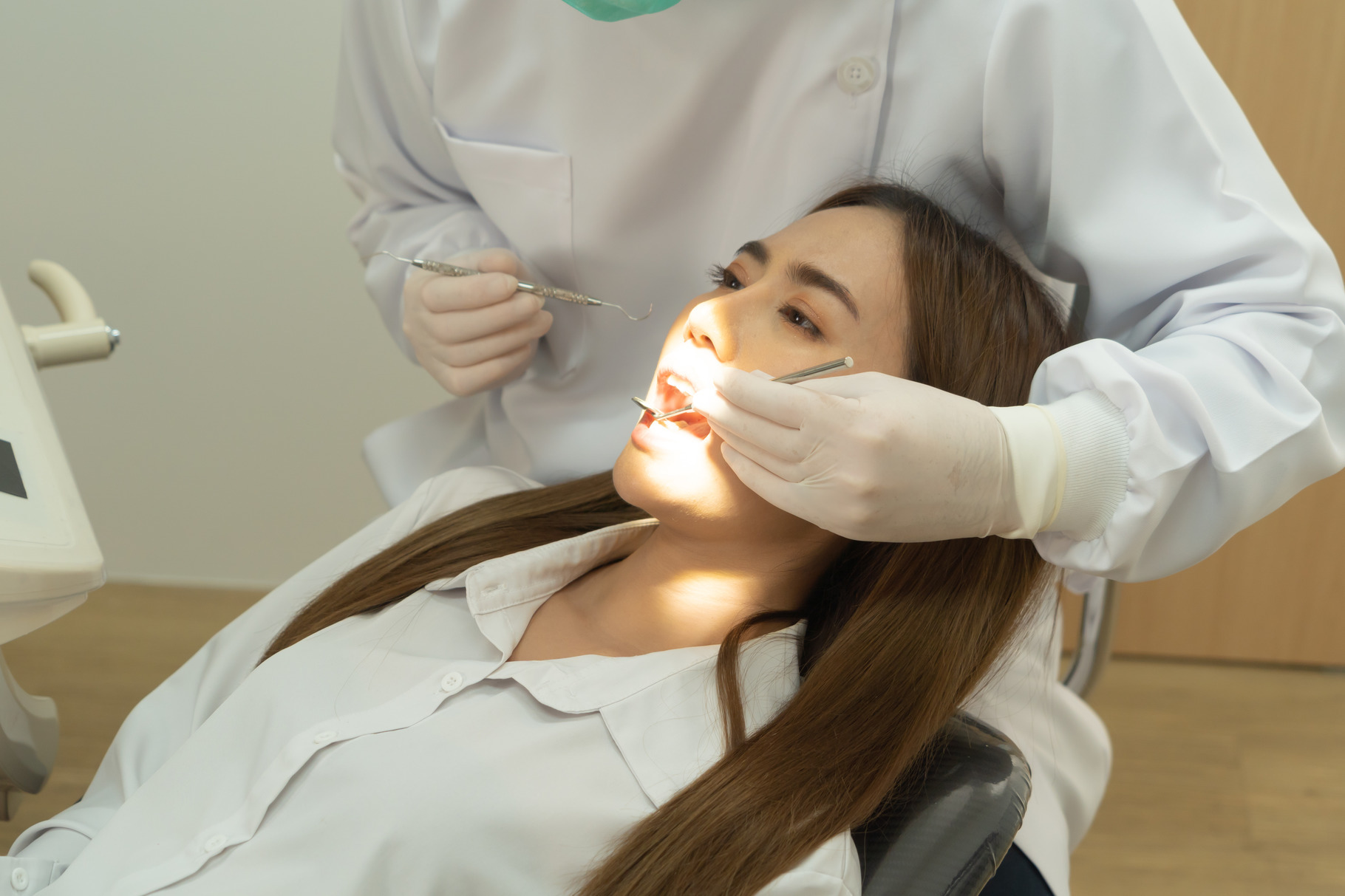A dentist checking up Asian woman's teeth by using dental mouth, a ...