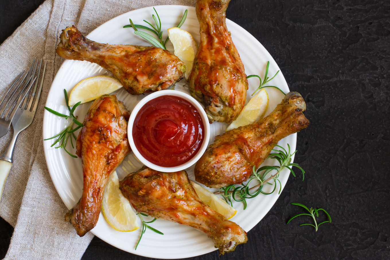 Roasted chicken drumstick in red sauce basil and lemon on a blac ...