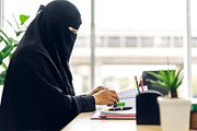 Arab businesswoman looking at desktop computer while sitting on ...