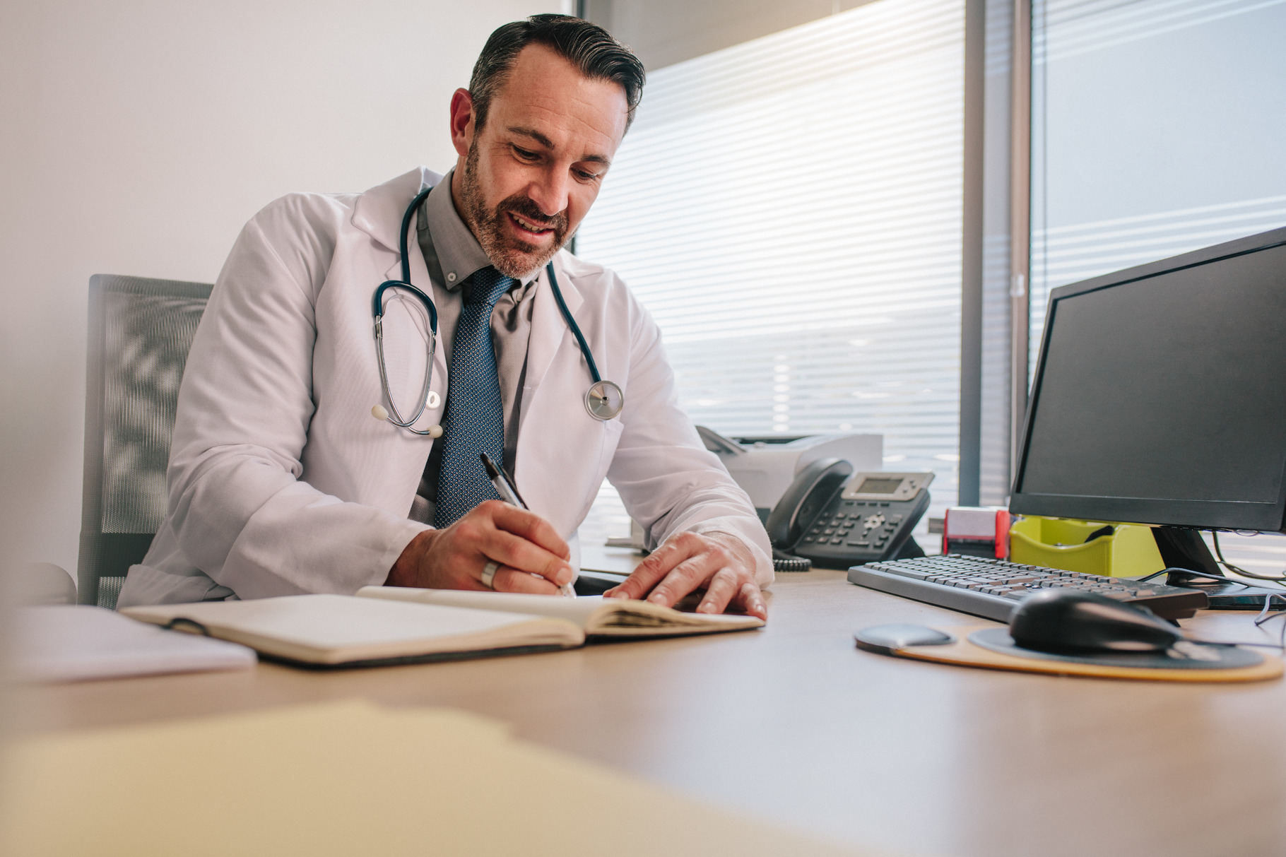 Doctor writing in his diary sitting, a Health & Medical Photo by Jacob Lund