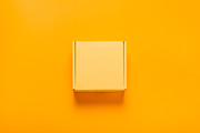 Simple yellow cardboard box on color background, top view, an ...