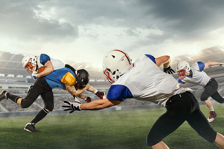 American football players in fight for goal at stadium in flashlights ...