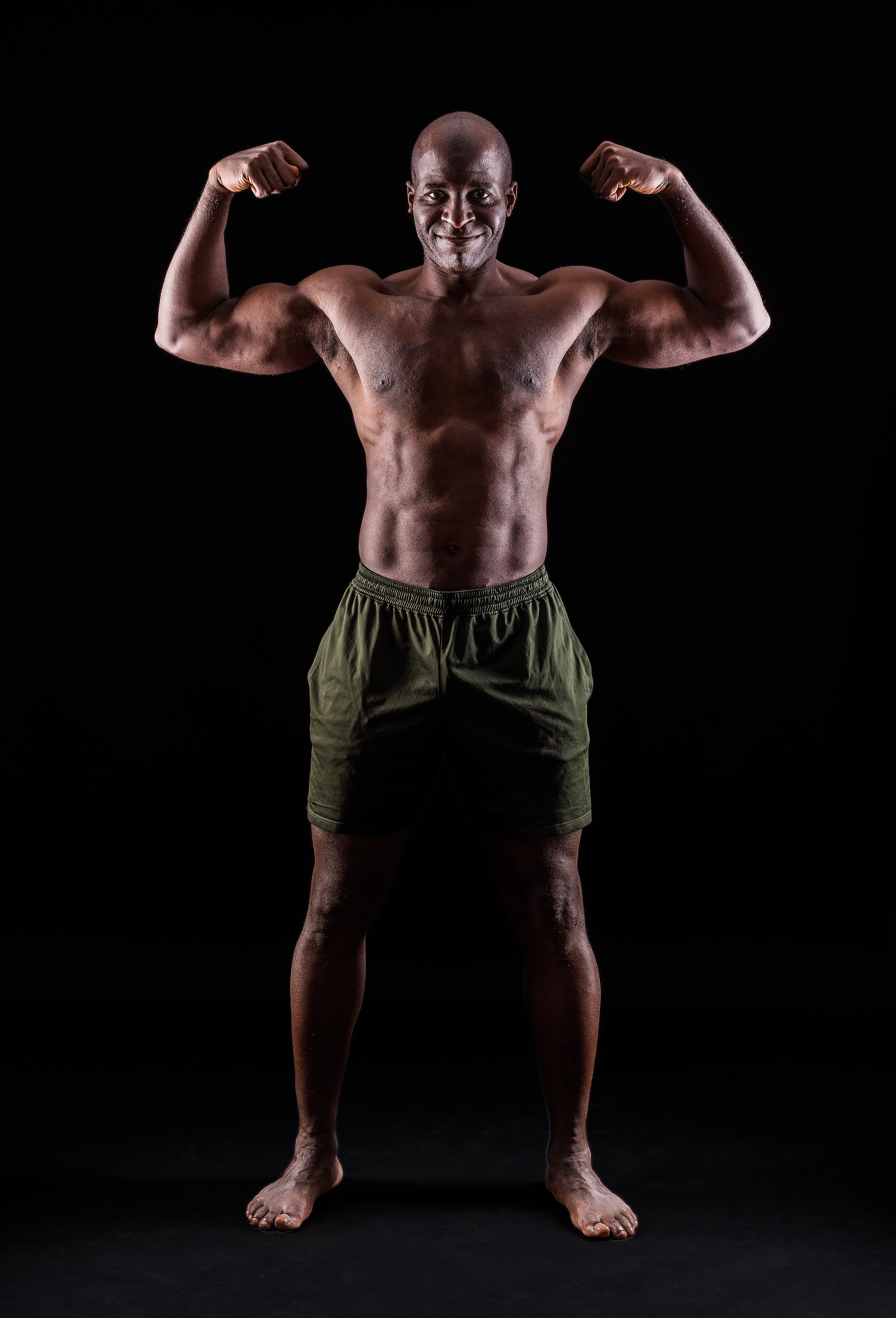 African American muscular man smiling flexing arm muscles on a black ...