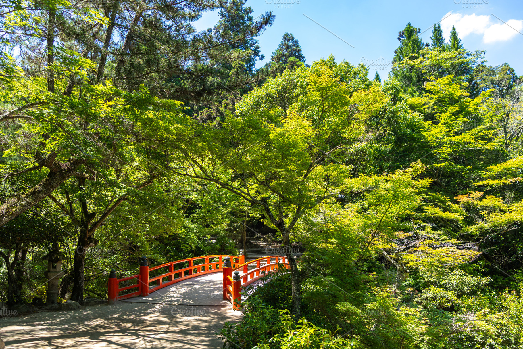 Traditional red bridge in lush forest of Miyajima Island, Japan, a ...