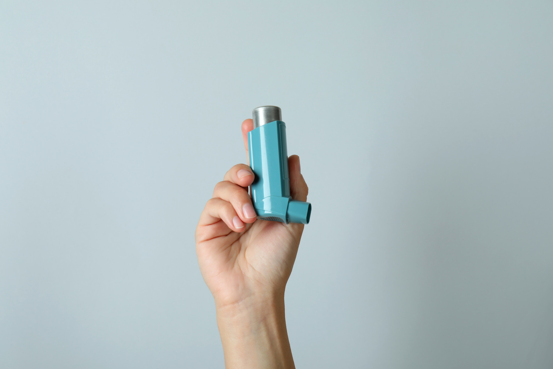 Female hand holds asthma inhaler on light gray background, a Health ...