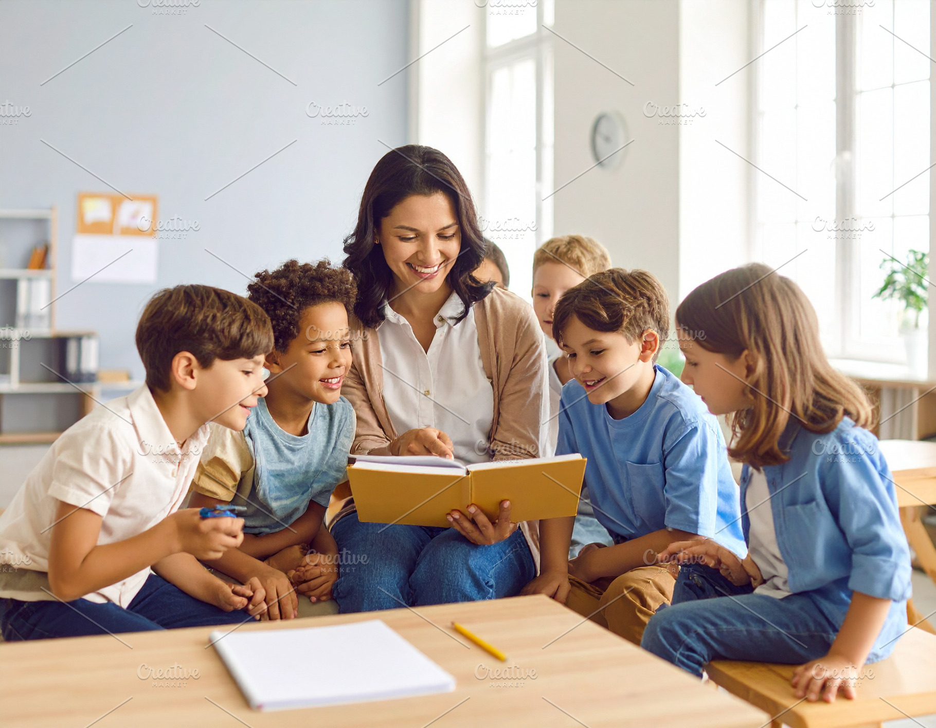 Teacher with a small group of children in a classroom pointing a, a ...