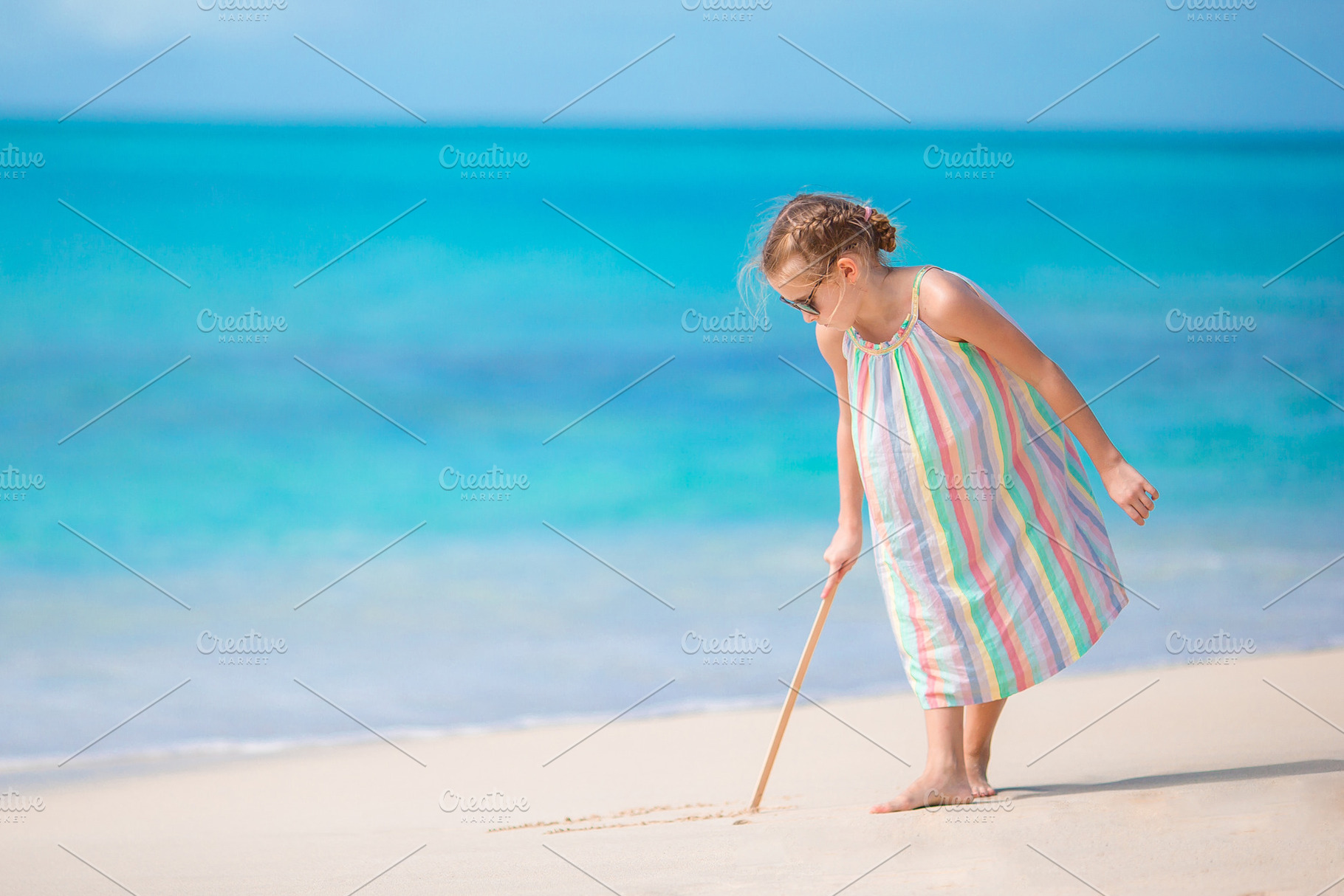 Adorable little girl at beach during summer vacation drawing on sand ...
