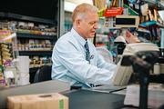 Senior cashier working at grocery store, a Person Photo by Jacob Lund