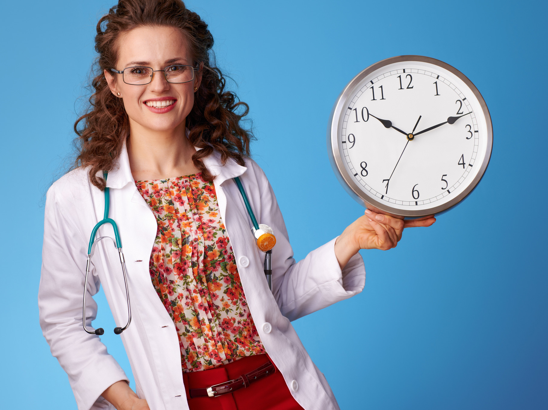Smiling paediatrician doctor showing clock on blue featuring doctor ...