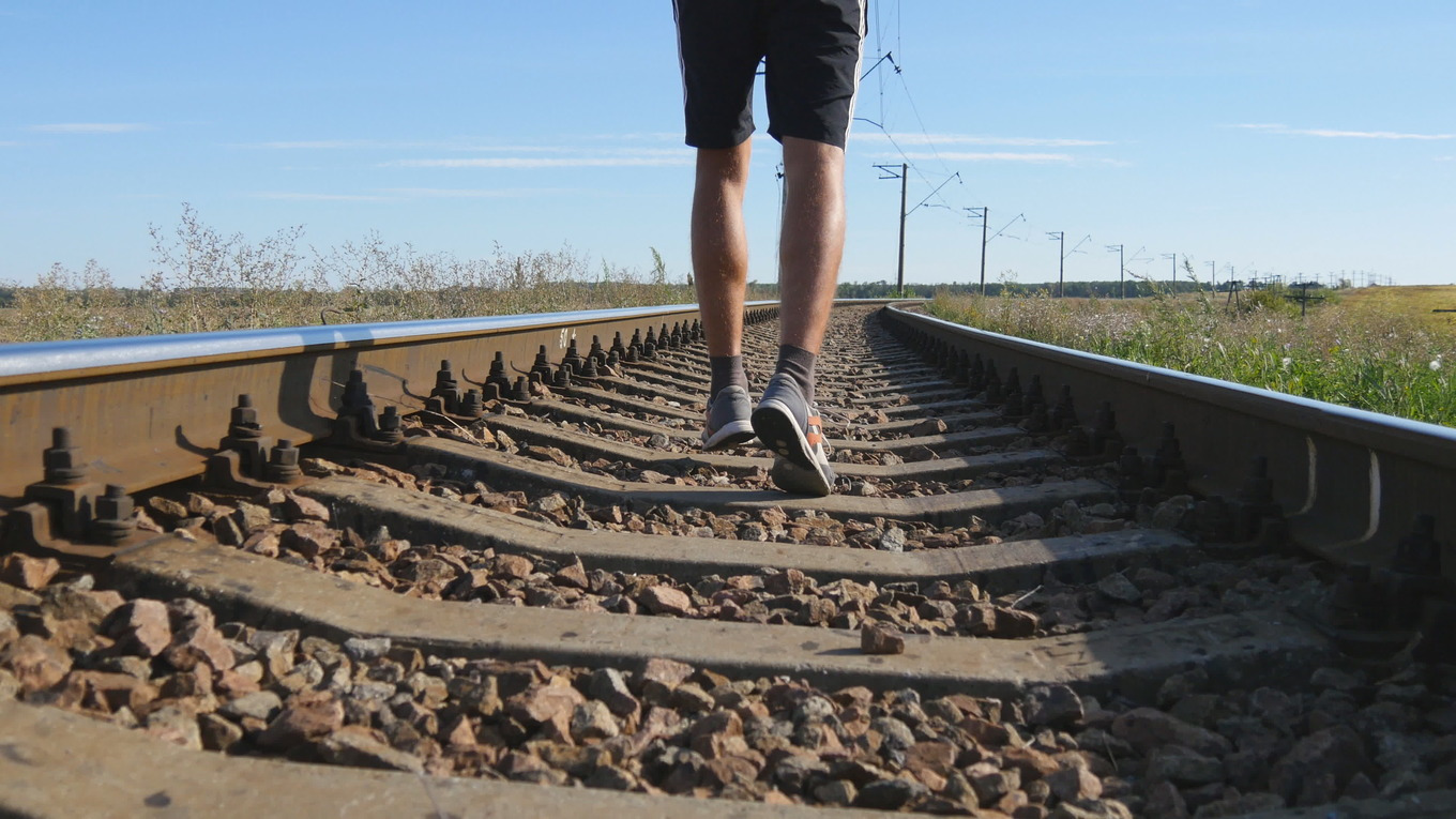 Male feet are running between rails on railroad tracks sprinting runner ...