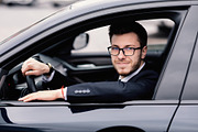 Cheerful business man driving alone, a Photo by Prostock-Studio
