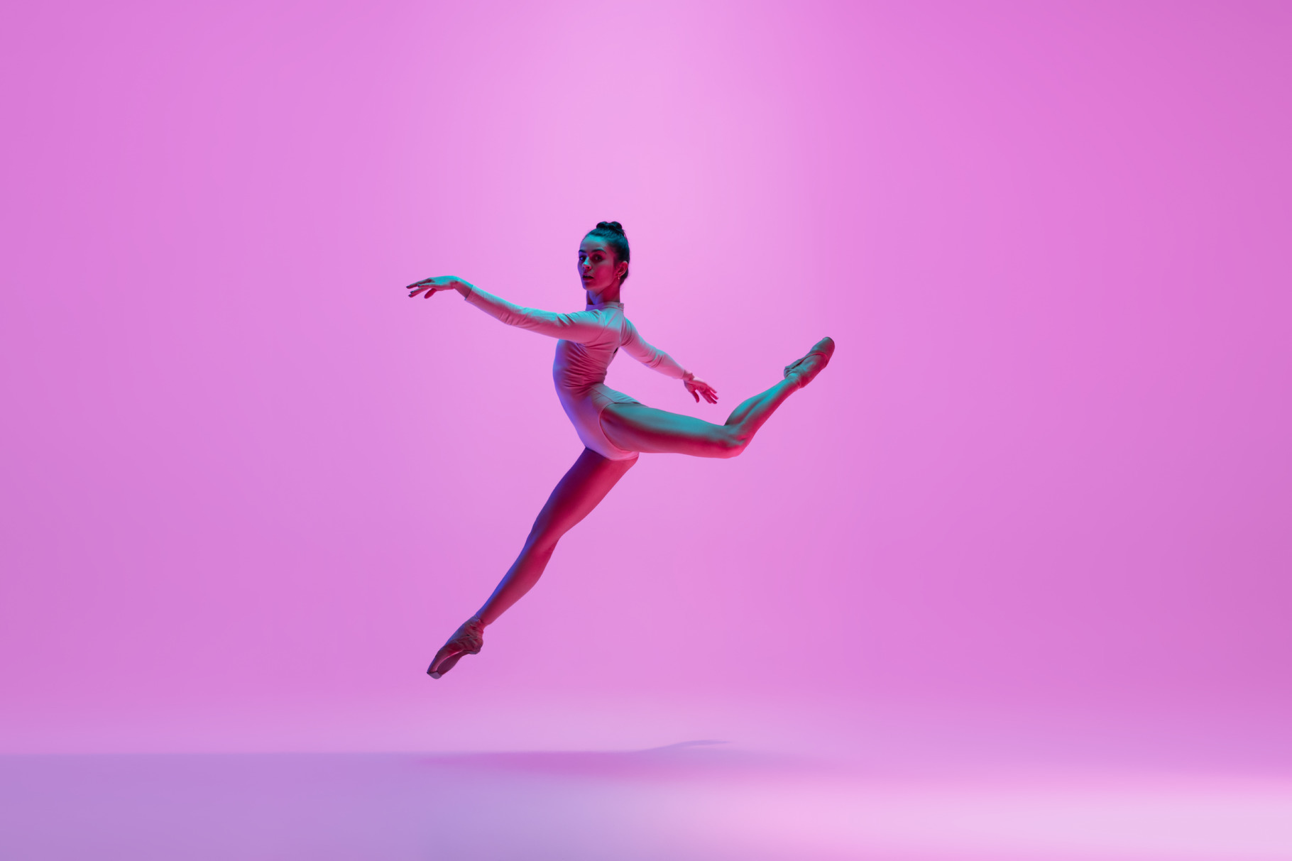 Young and graceful ballet dancer isolated on pink studio background in ...
