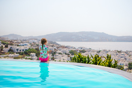Adorable little girls on the edge of outdoor swimming pool with ...