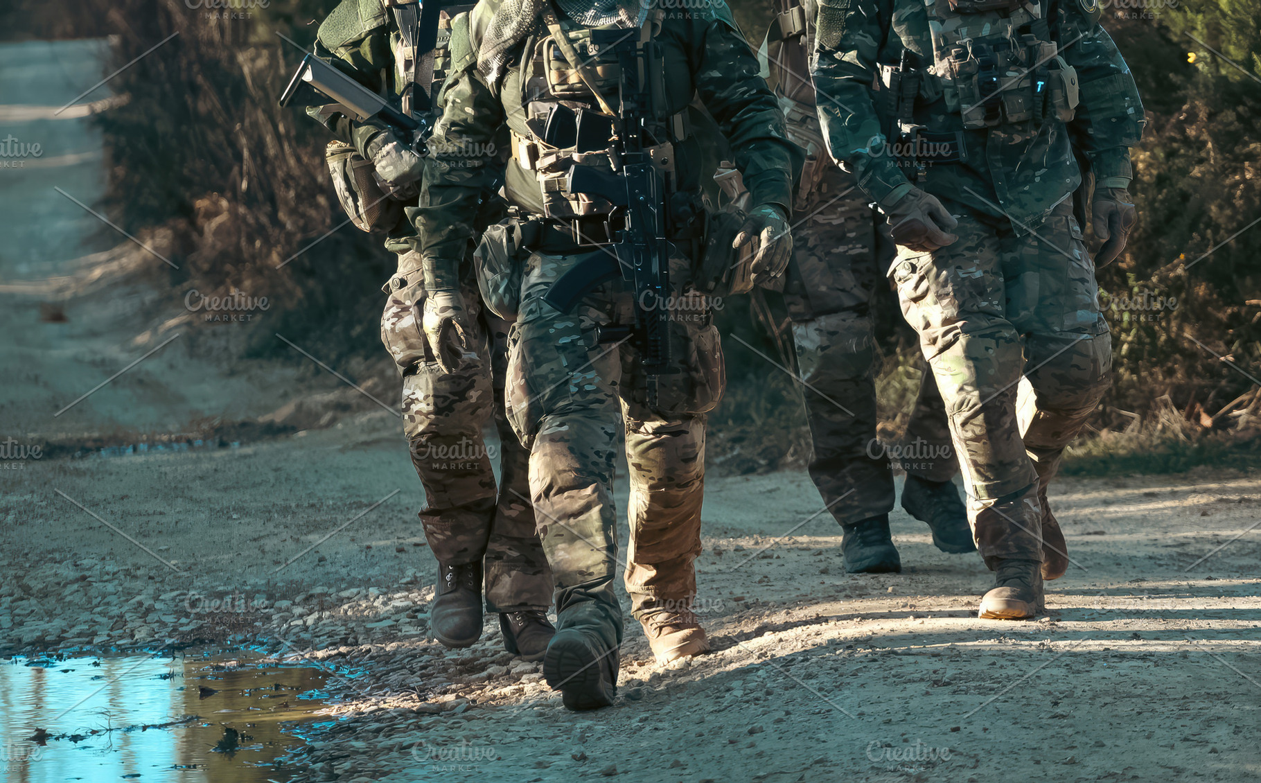 Soldiers walking on dirt road carrying weapons and wearing camouflage ...