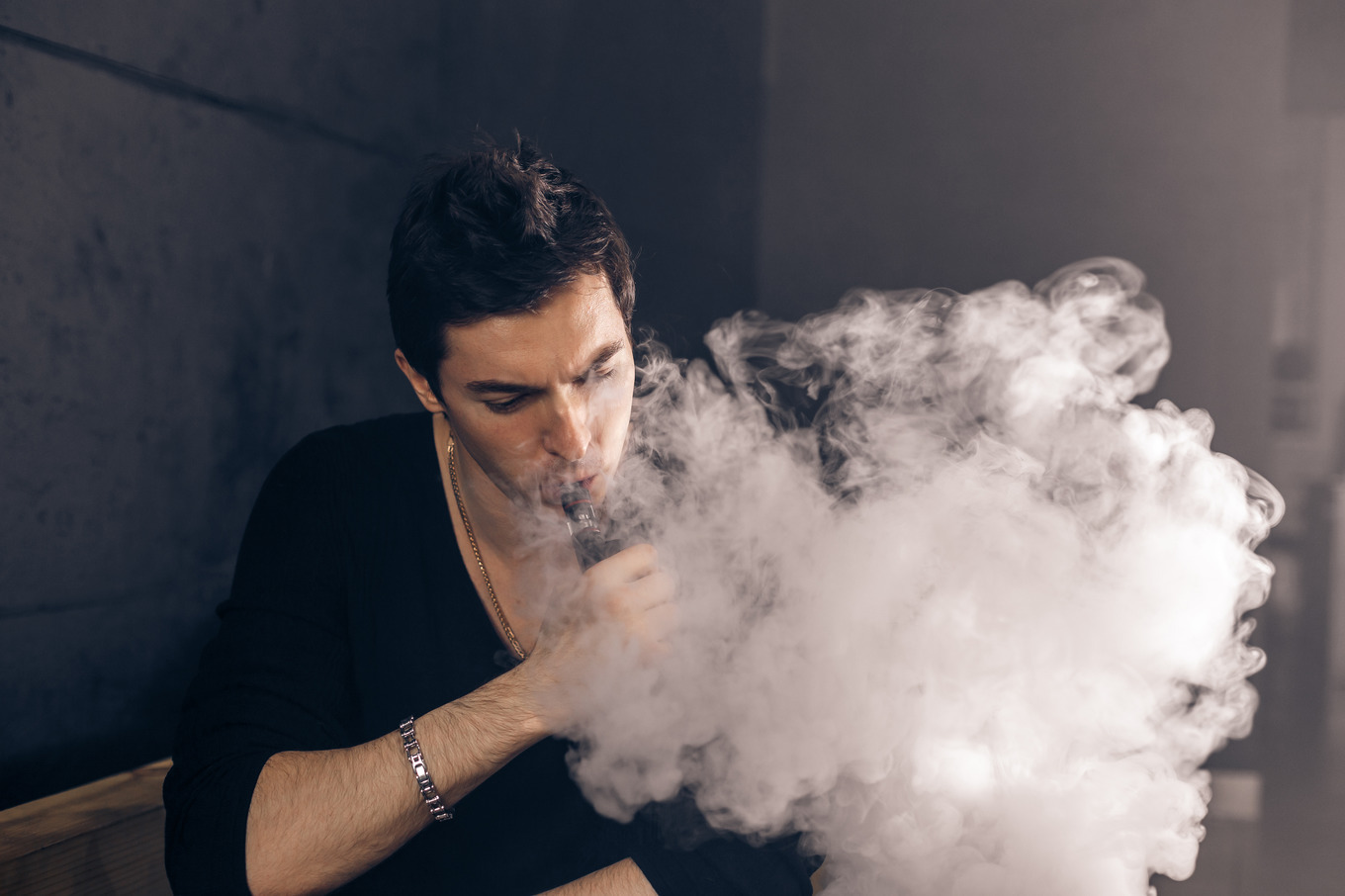 Vaping man holding a mod a cloud of vapor black background featuring ...