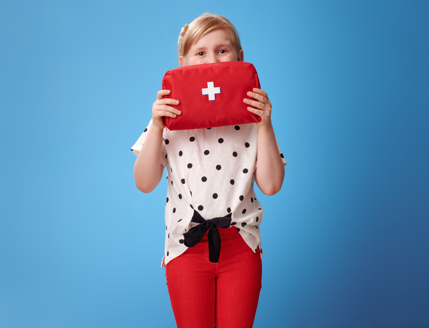 happy child holding first-aid kit in front of face on blue | People ...