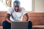 Young black african man relaxing using laptop computer working a ...