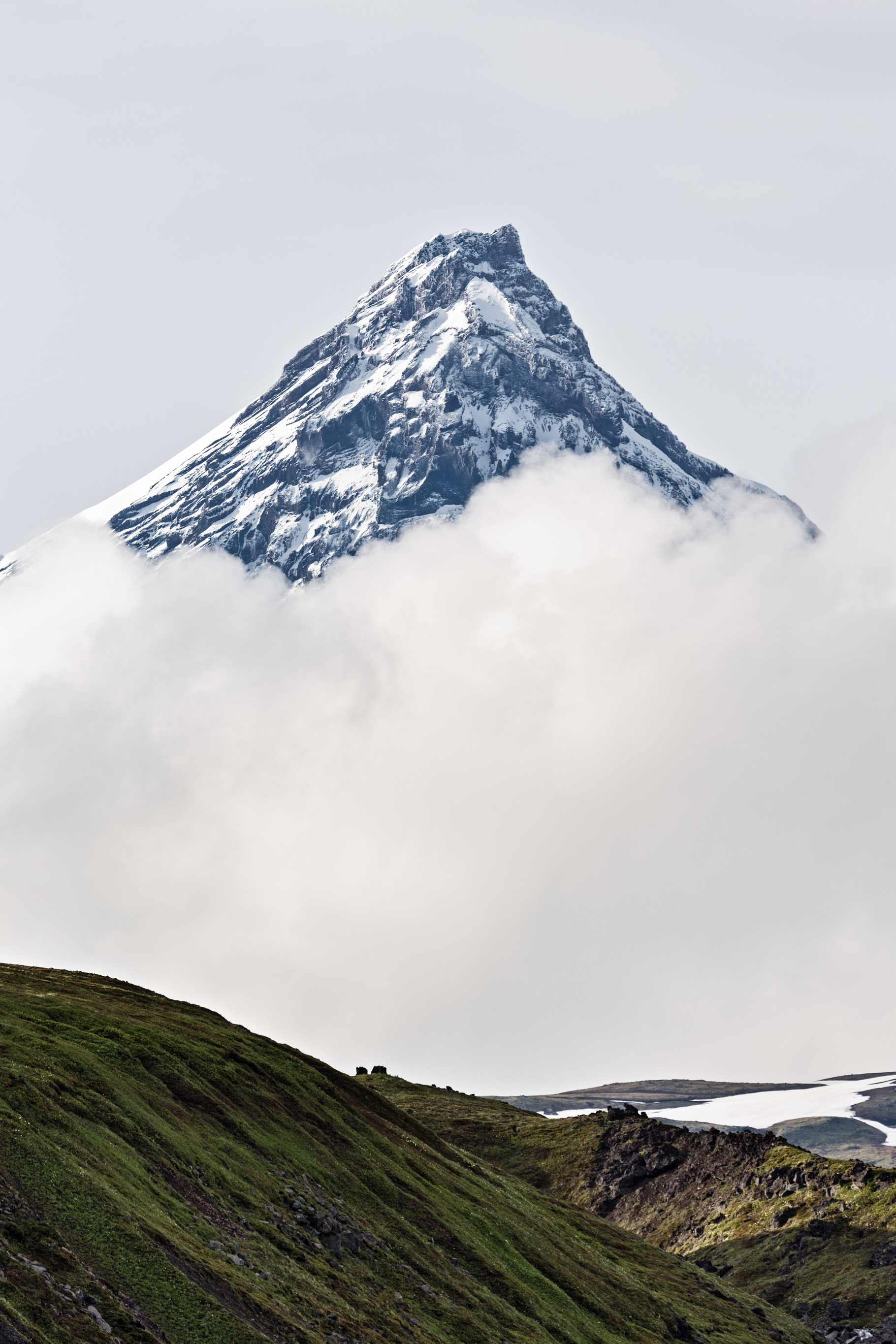 Snowy rocky volcano cone in clouds, a Nature Photo by Alexander-Piragis