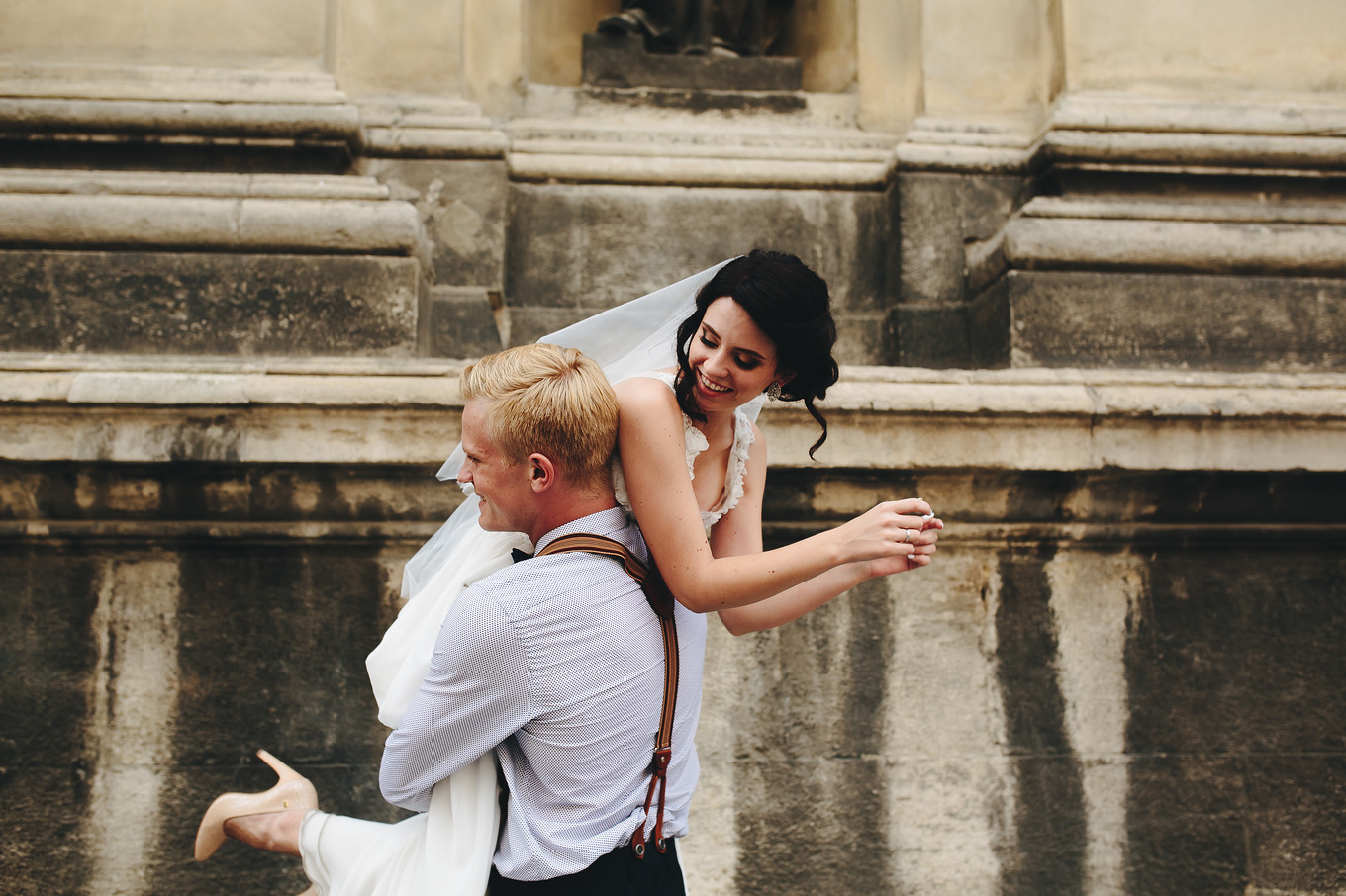 Groom carries bride in his arms containing bride, groom, and love, a ...