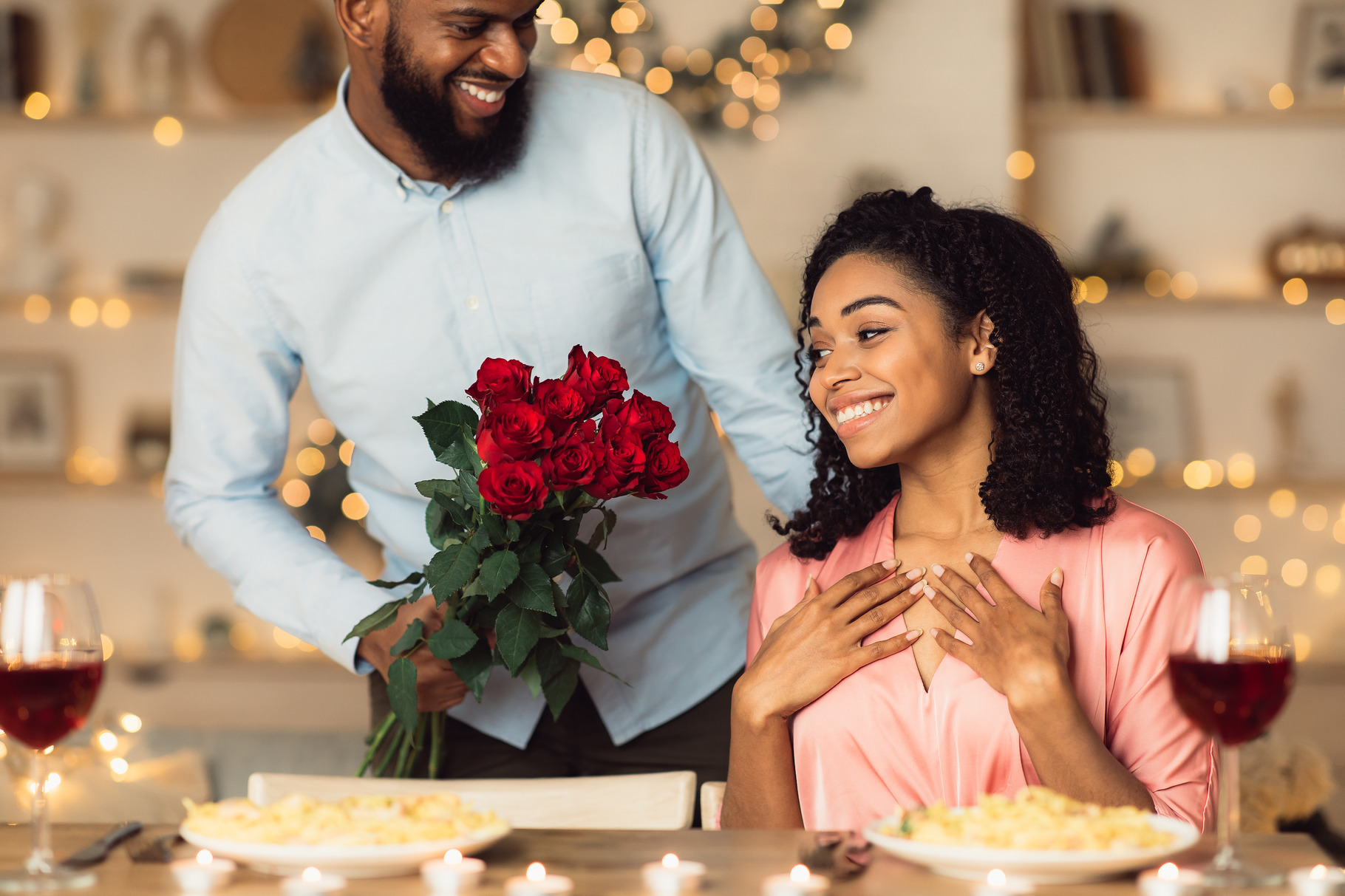 Young black man giving red roses to woman, a Photo by Prostock-Studio