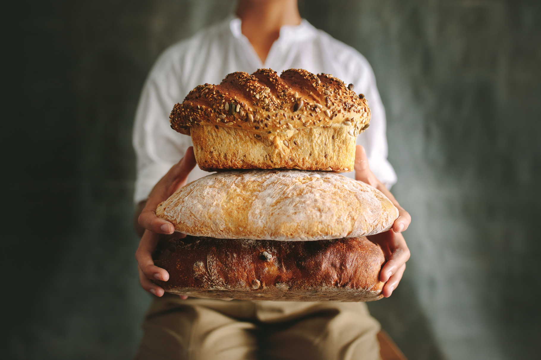 Baker showing various loaf breads, a Person Photo by Jacob Lund