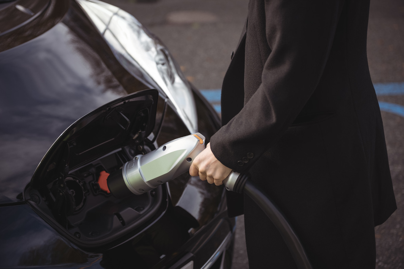 Man charging electric car at electric vehicle charging station, a Photo ...