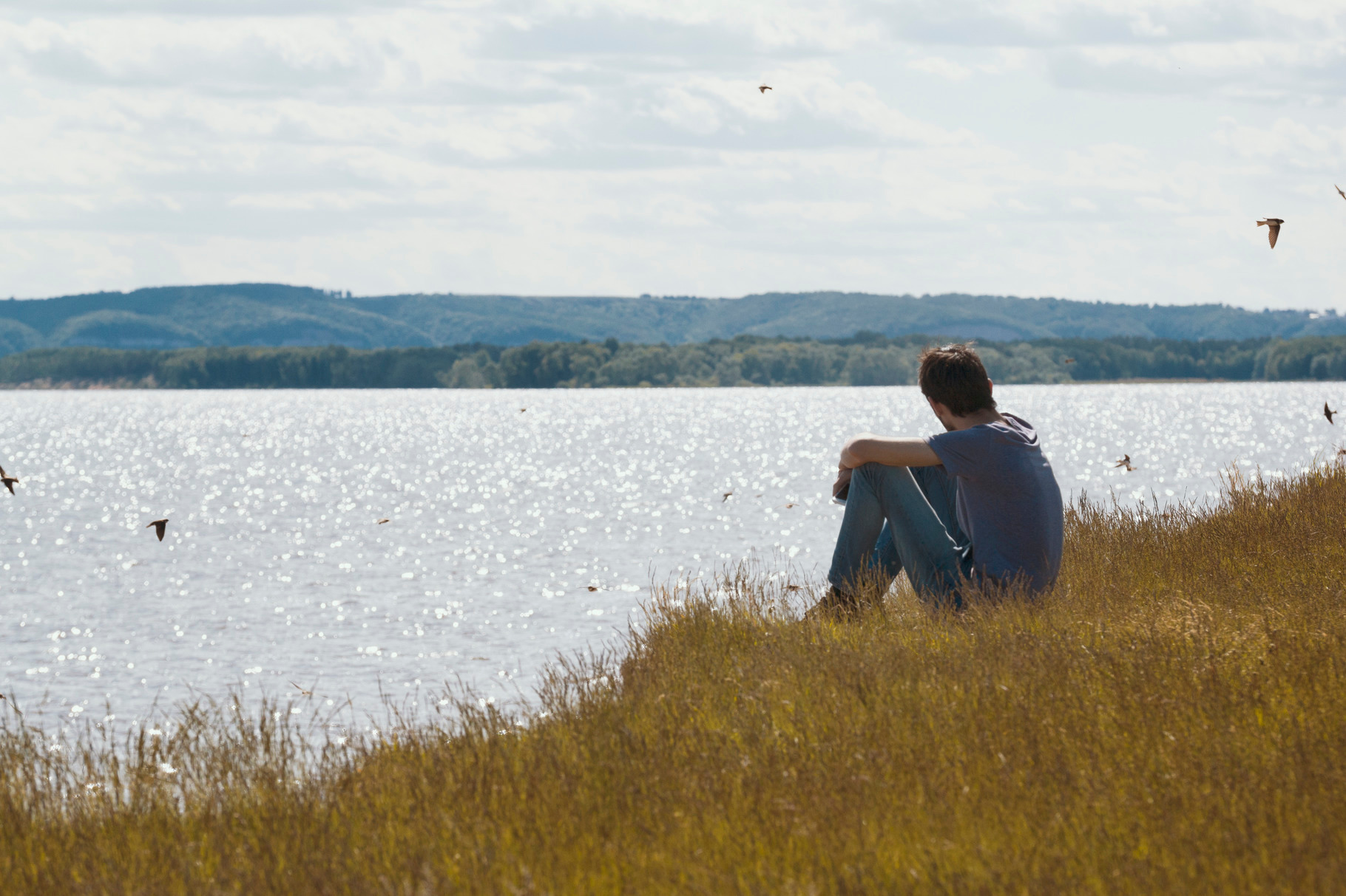 Young sad man sitting near the river, a Person Photo by Barcelona_dreams