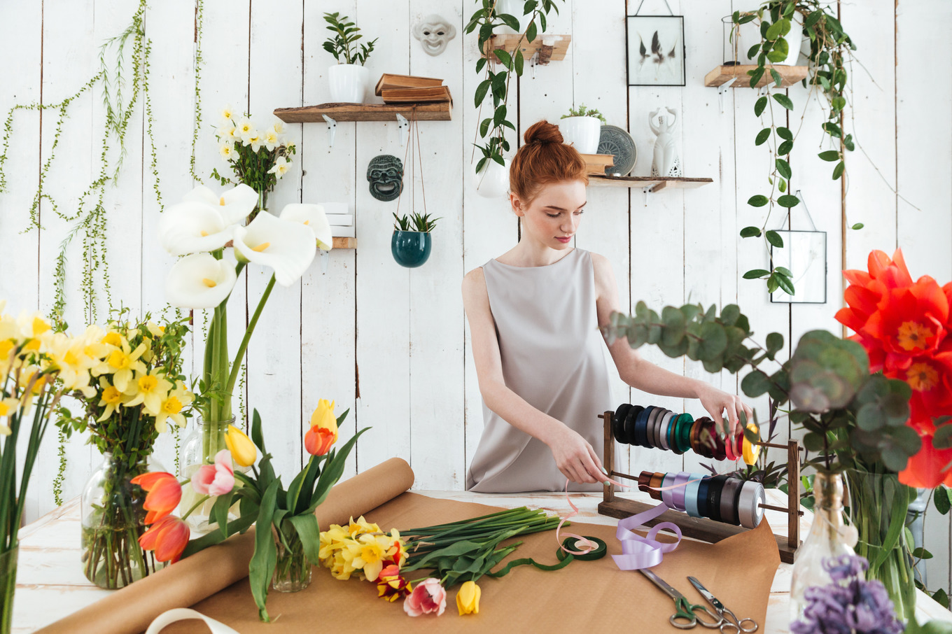 Young woman florist making bouquet with flowers and ribbons, a Person ...