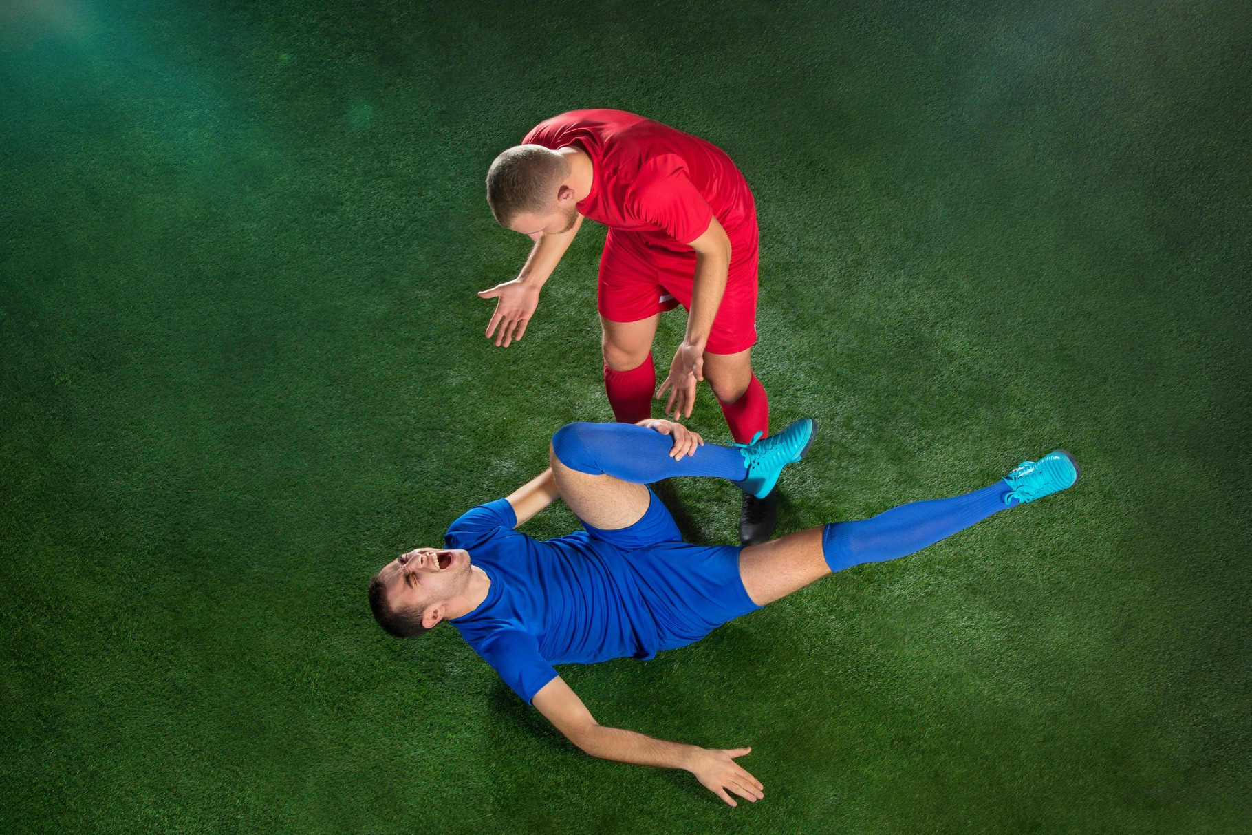 Male soccer player suffering from leg injury on football green field ...