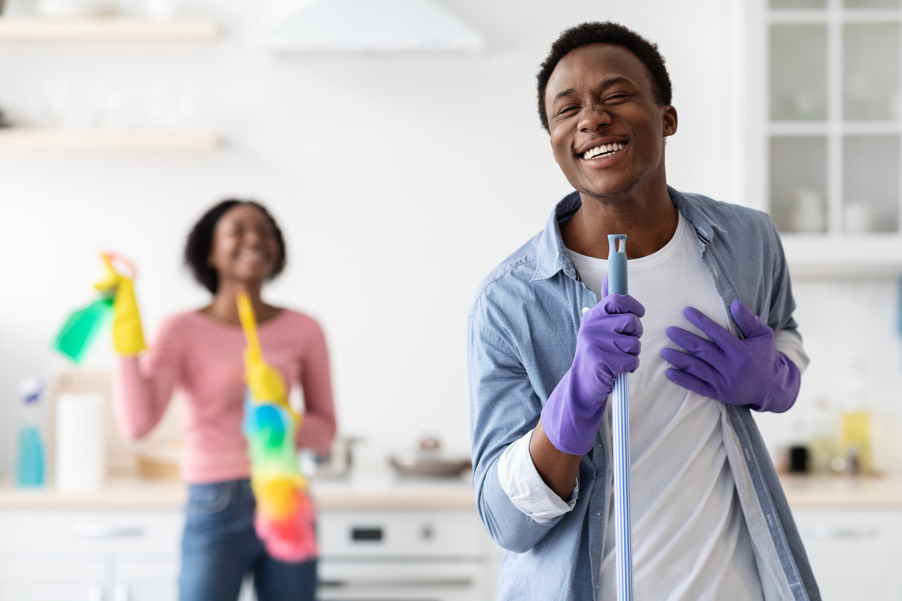 Black guy having fun with his girlfriend while cleaning kitchen, a ...