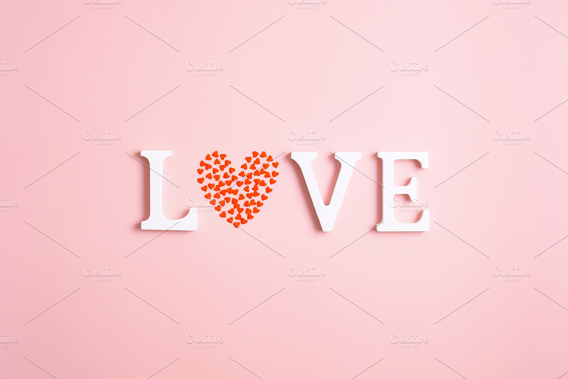 Word Love made of white letters and heart shaped confetti on pink ...