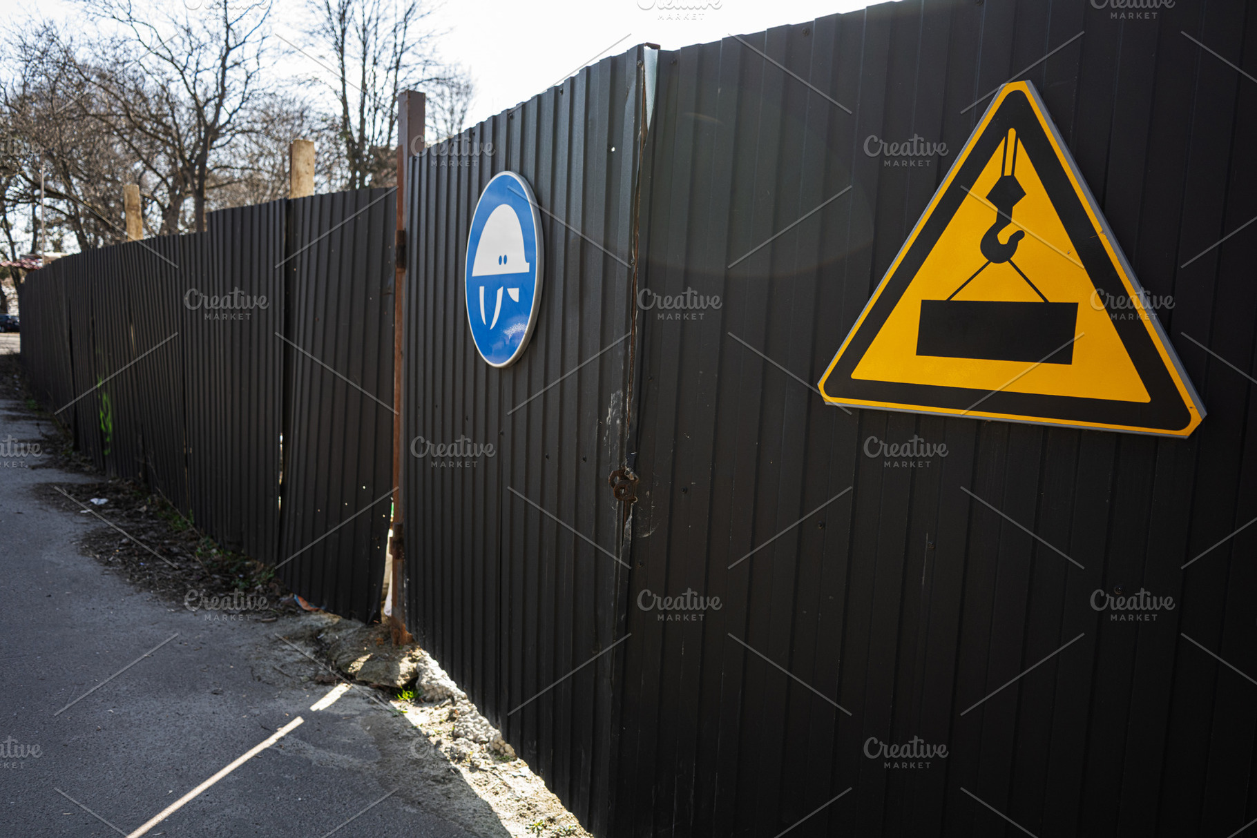 Construction site warning signs on a perimeter fence under a clear sky ...