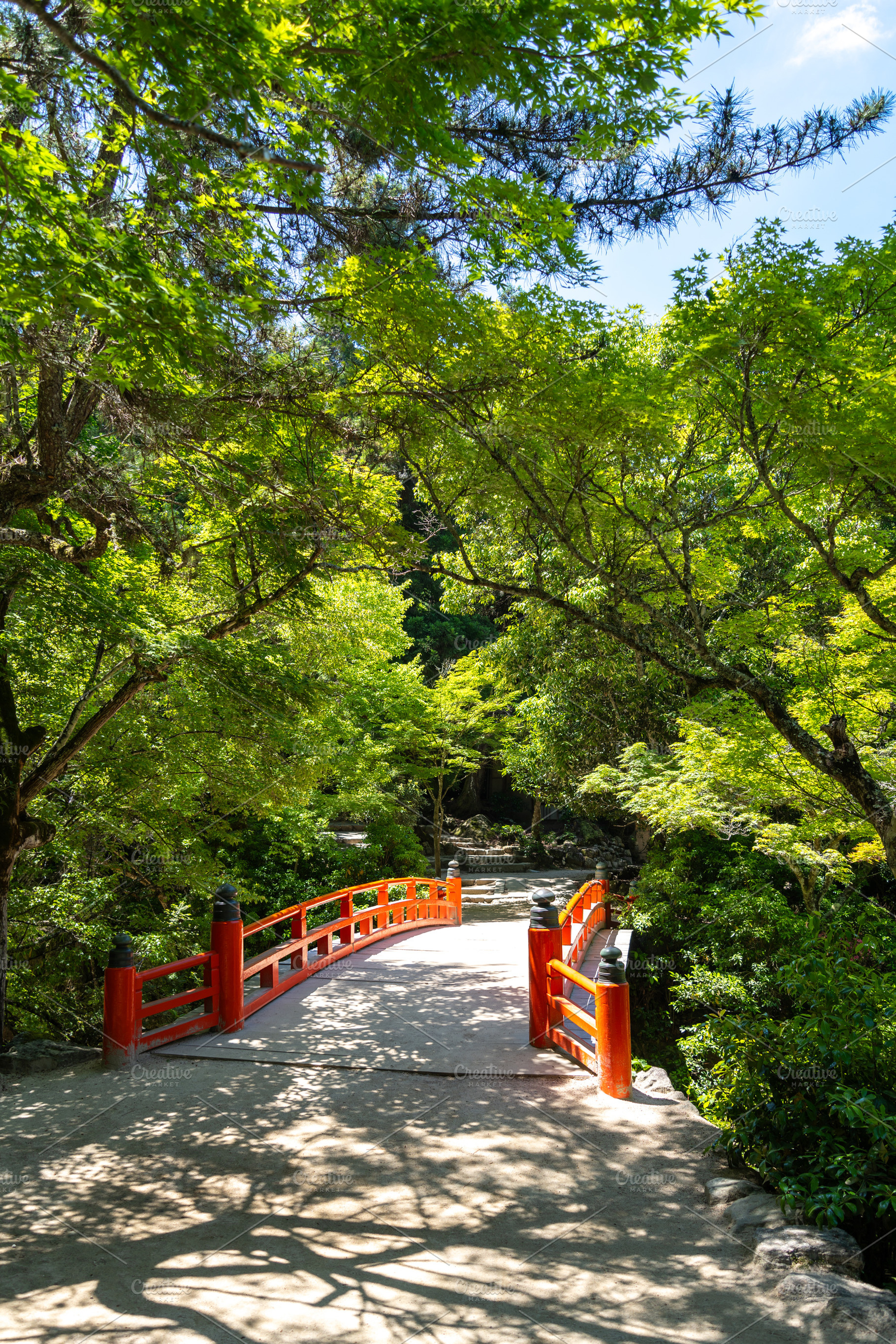 Traditional red bridge in lush forest of Miyajima Island, Japan, a ...