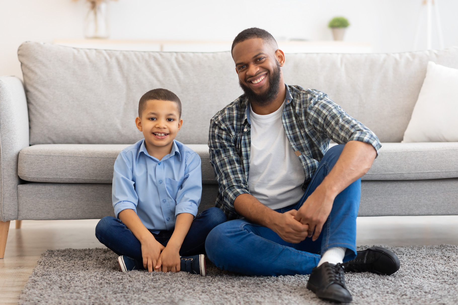 Black Father And Son Posing Sitting On Floor At Home, a Background ...